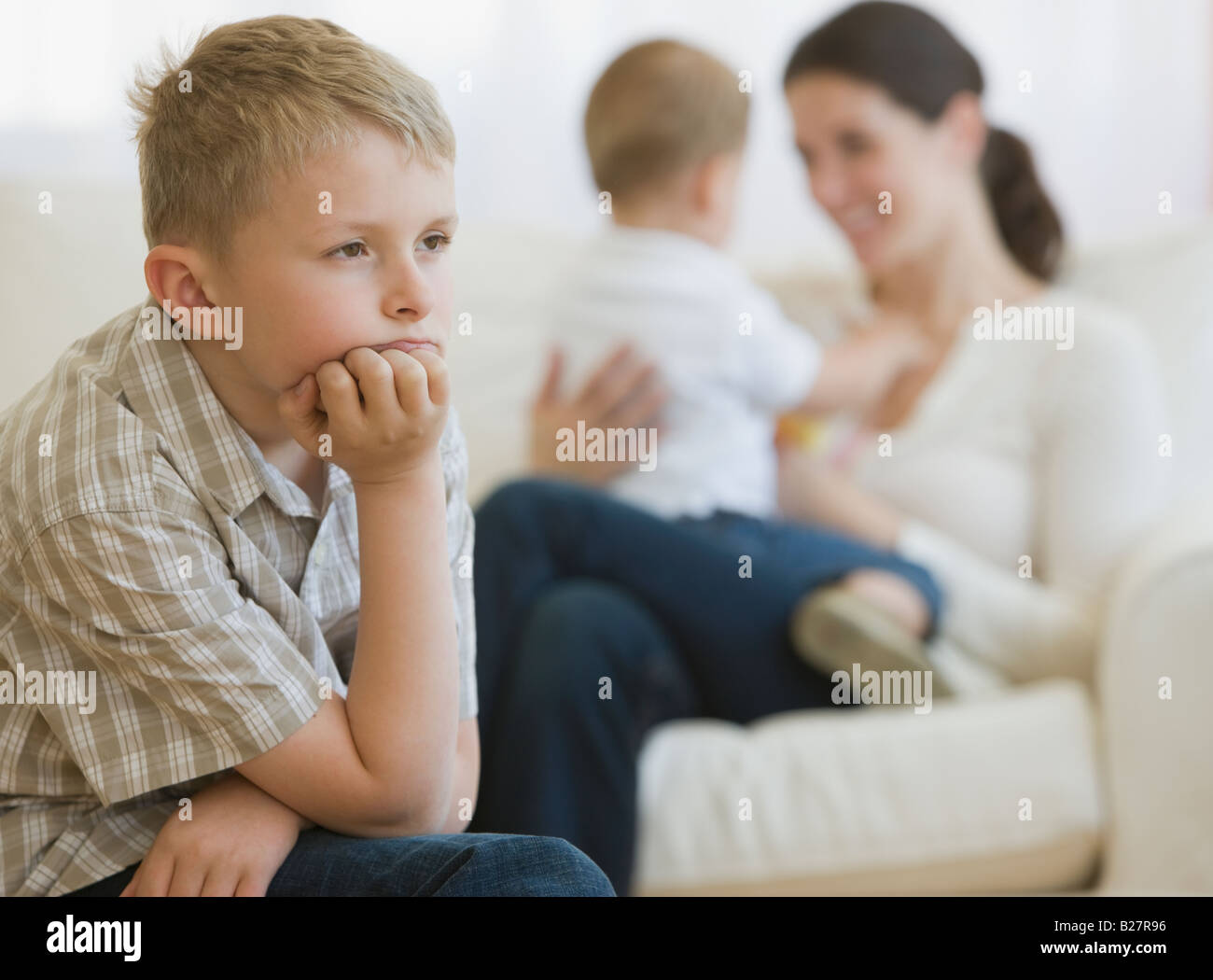 Boy thinking in front of mother and baby Stock Photo - Alamy