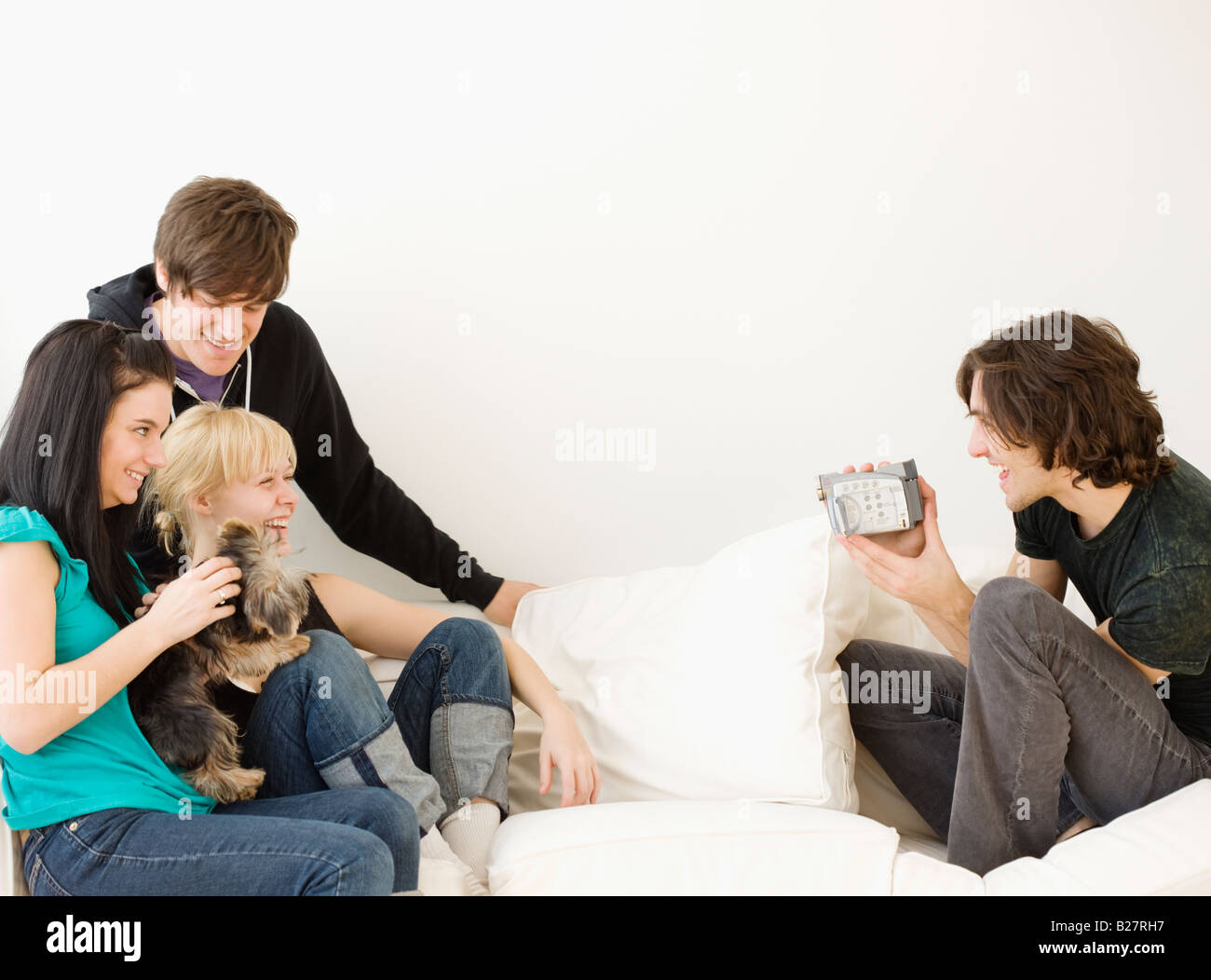 Man video recording friends on sofa Stock Photo - Alamy