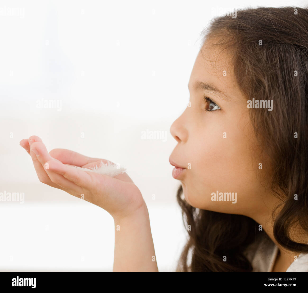 Hispanic girl blowing on feather in hand Stock Photo - Alamy