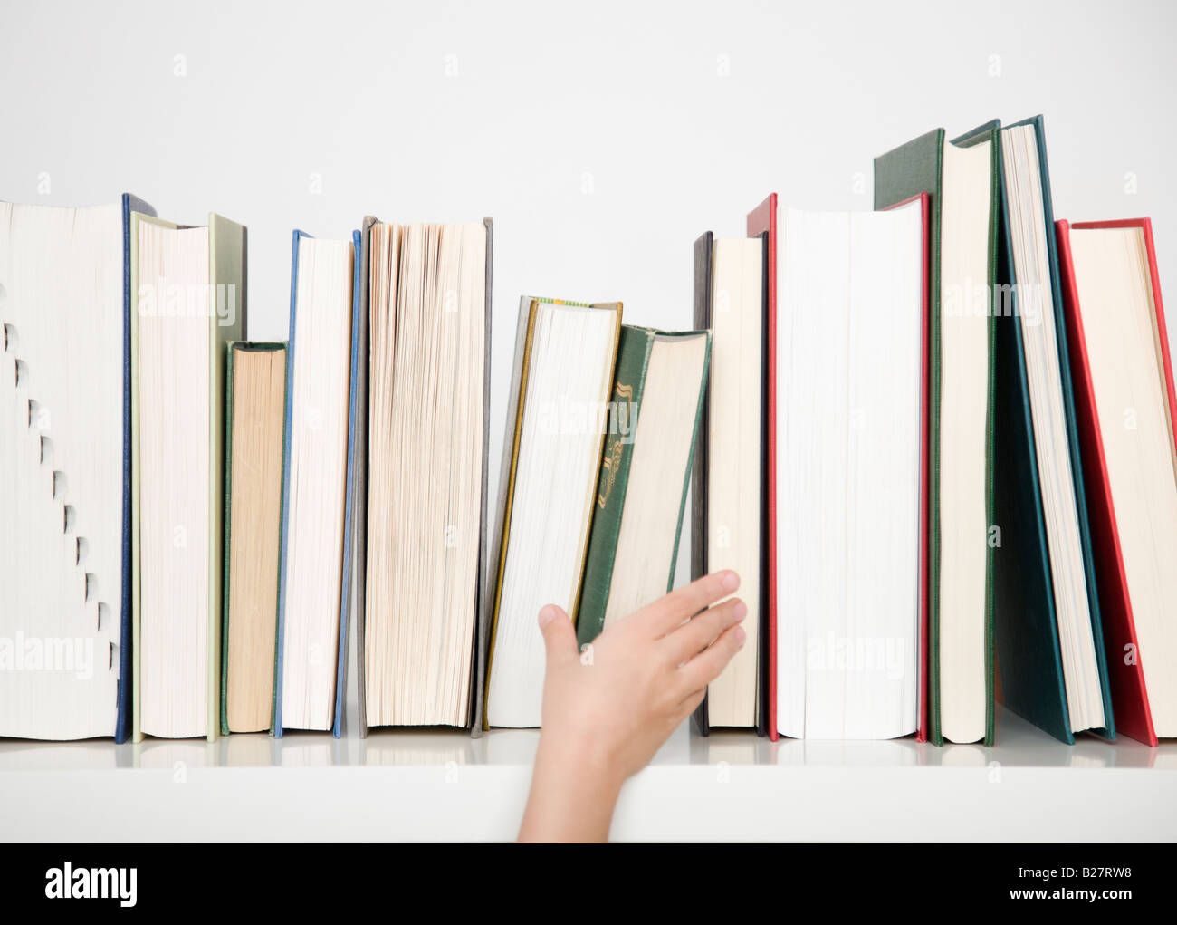 Child reaching for book on shelf Stock Photo - Alamy