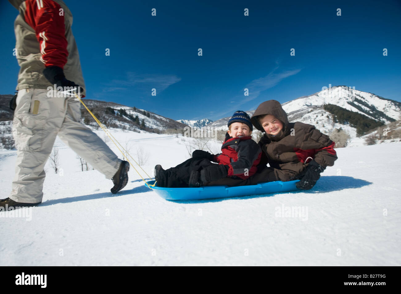 Father pulling children on sled Stock Photo - Alamy