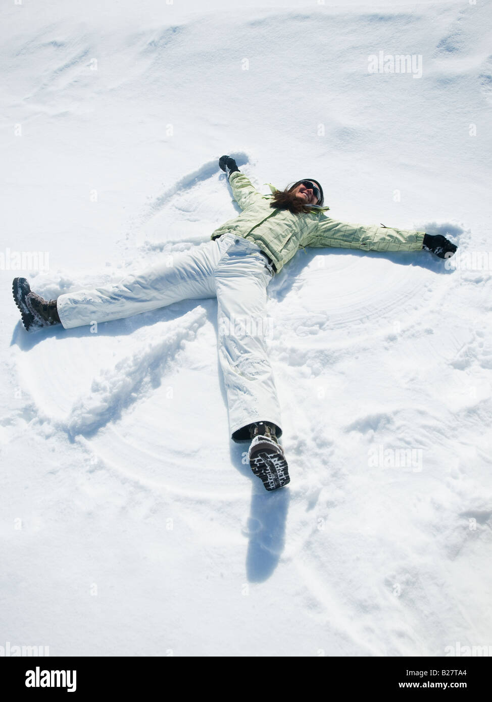 Woman making snow angel Stock Photo - Alamy