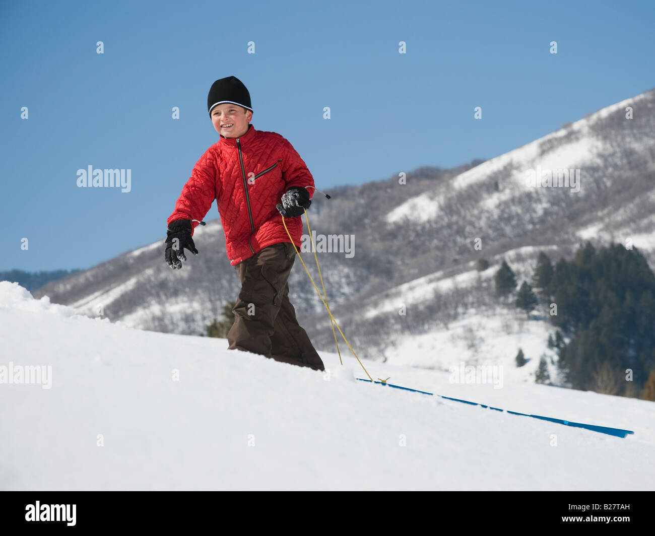 Boy pulling sled in snow Stock Photo - Alamy