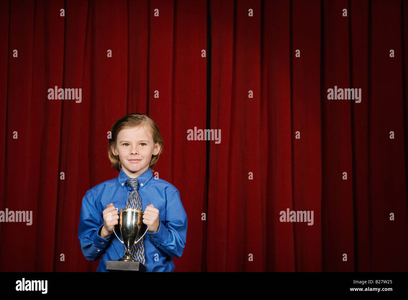 Boy holding trophy on stage Stock Photo - Alamy