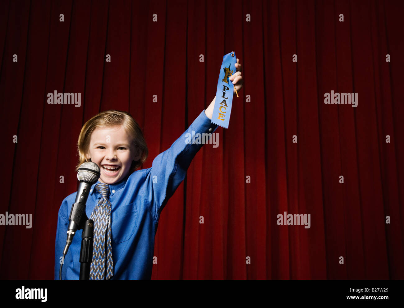 Boy holding first place ribbon on stage Stock Photo - Alamy