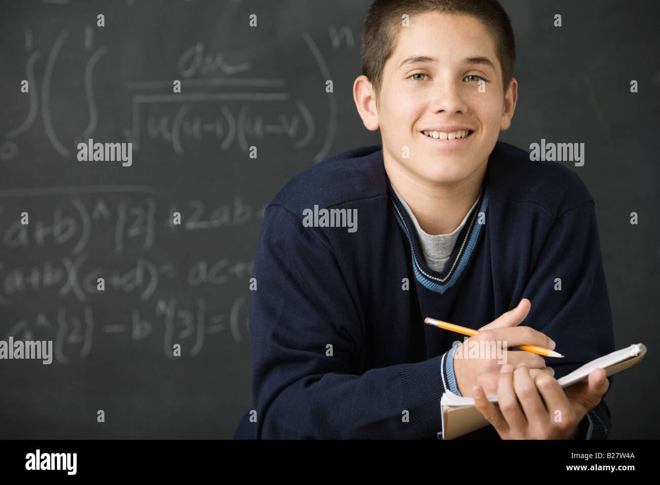 Boy holding notebook in front of blackboard Stock Photo - Alamy