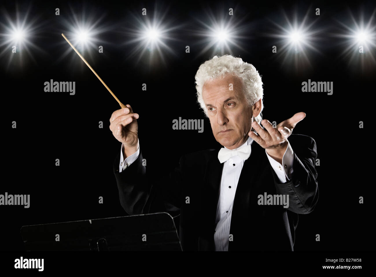 Man in tuxedo conducting under lights Stock Photo - Alamy