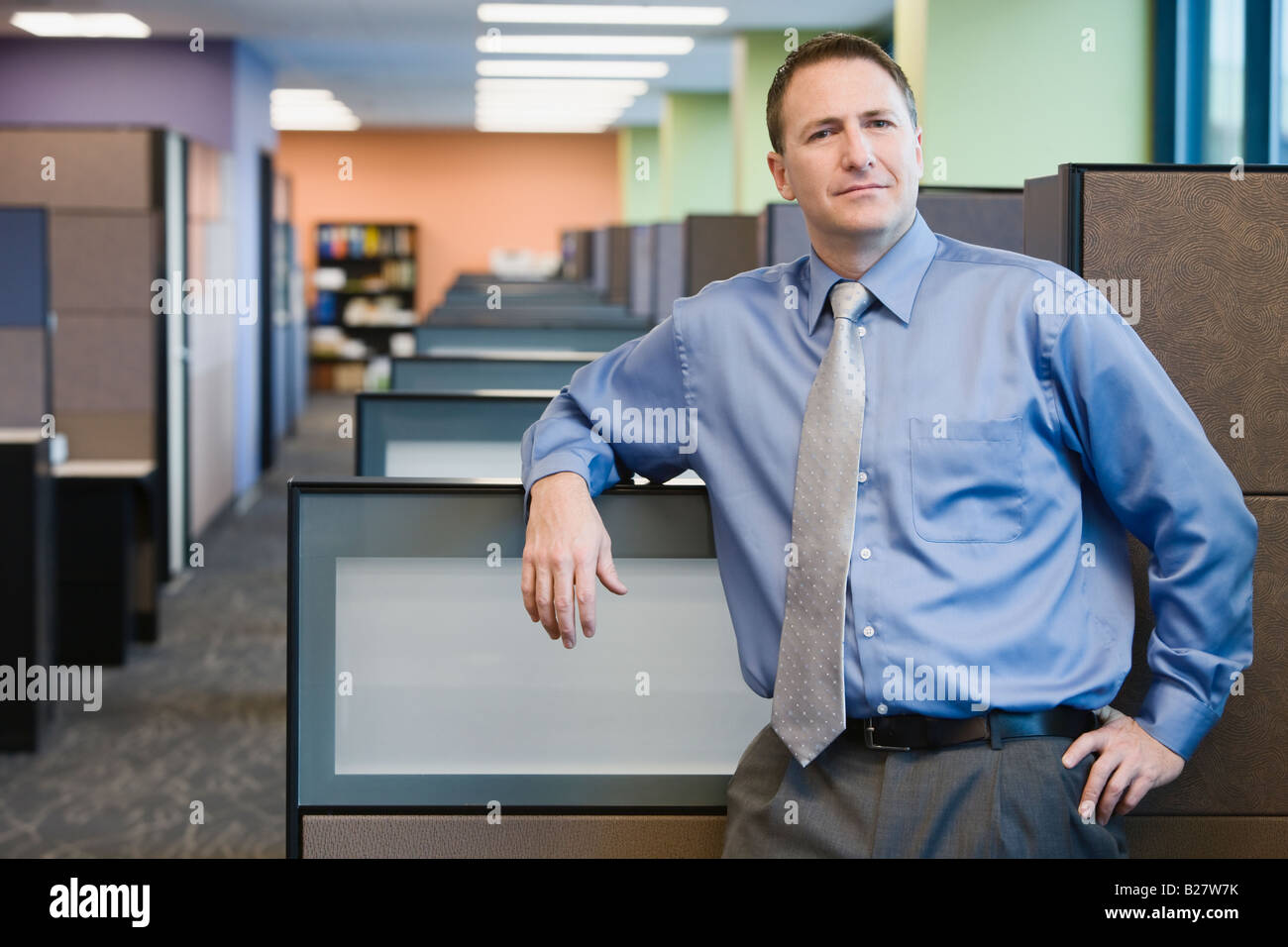 Businessman leaning on cubicle wall Stock Photo - Alamy