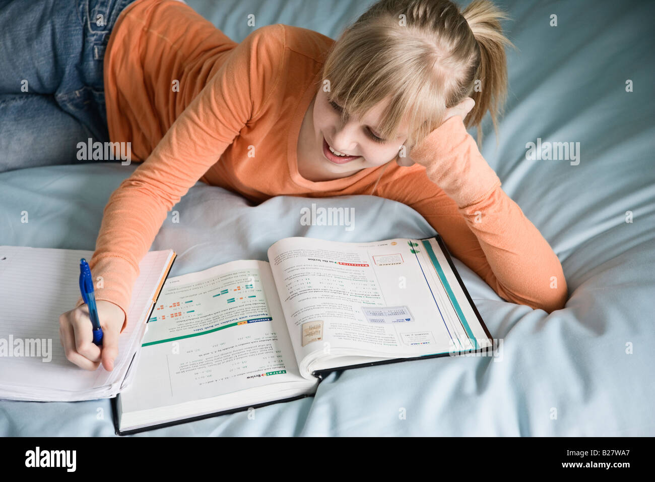 Girl doing homework on bed Stock Photo - Alamy