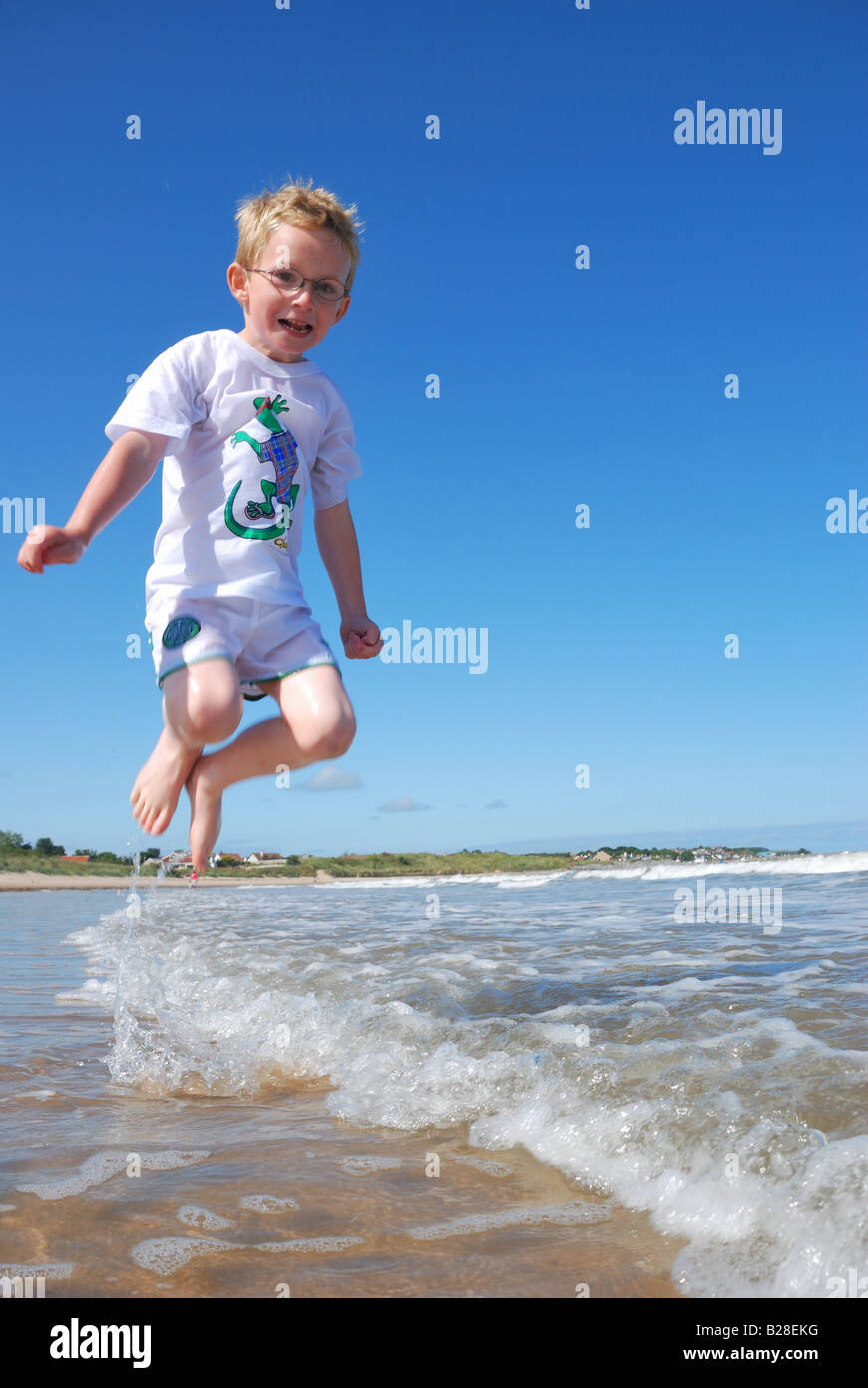 Boy jumping the waves at the Beach Stock Photo - Alamy