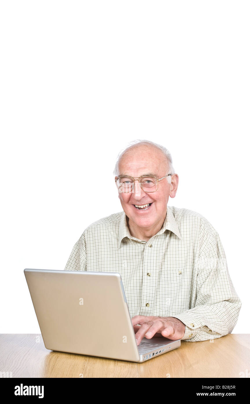 An elderly man at a desk looking at a lap top computer screen and ...