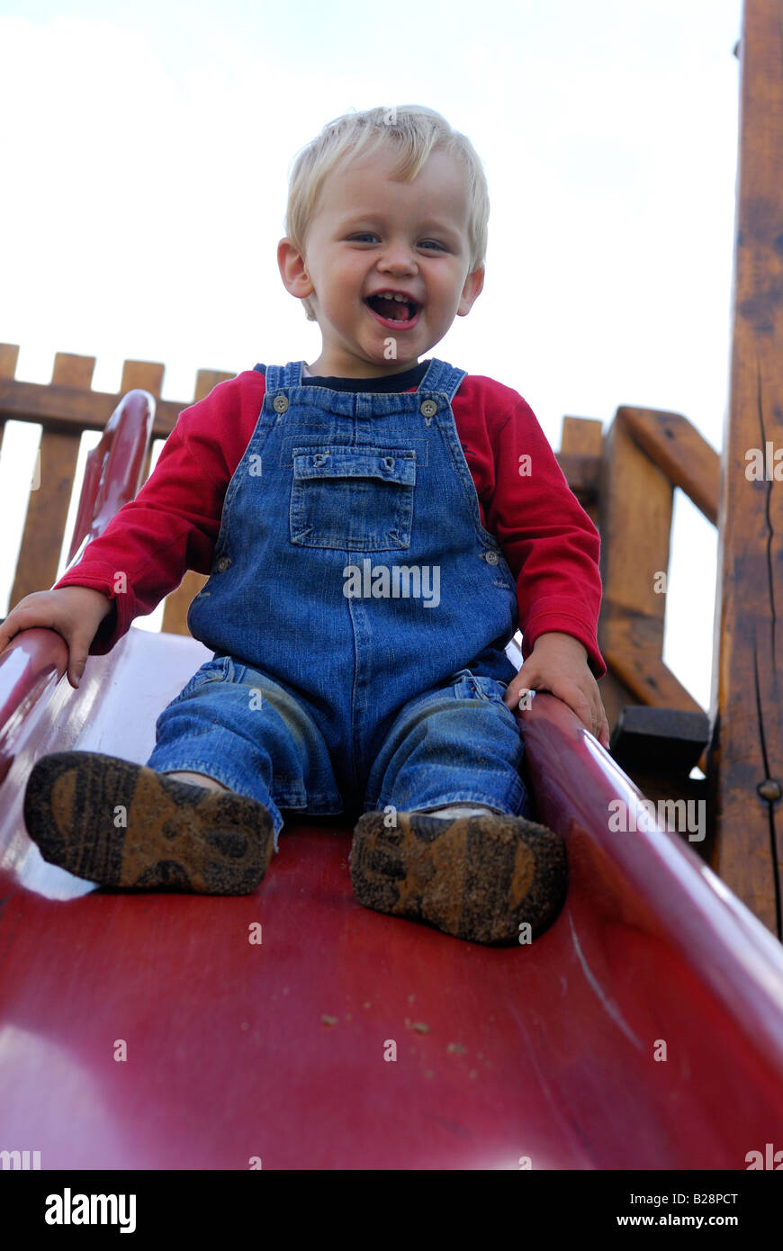 Baby blonde boy sliding down the slide on the playground Stock Photo ...