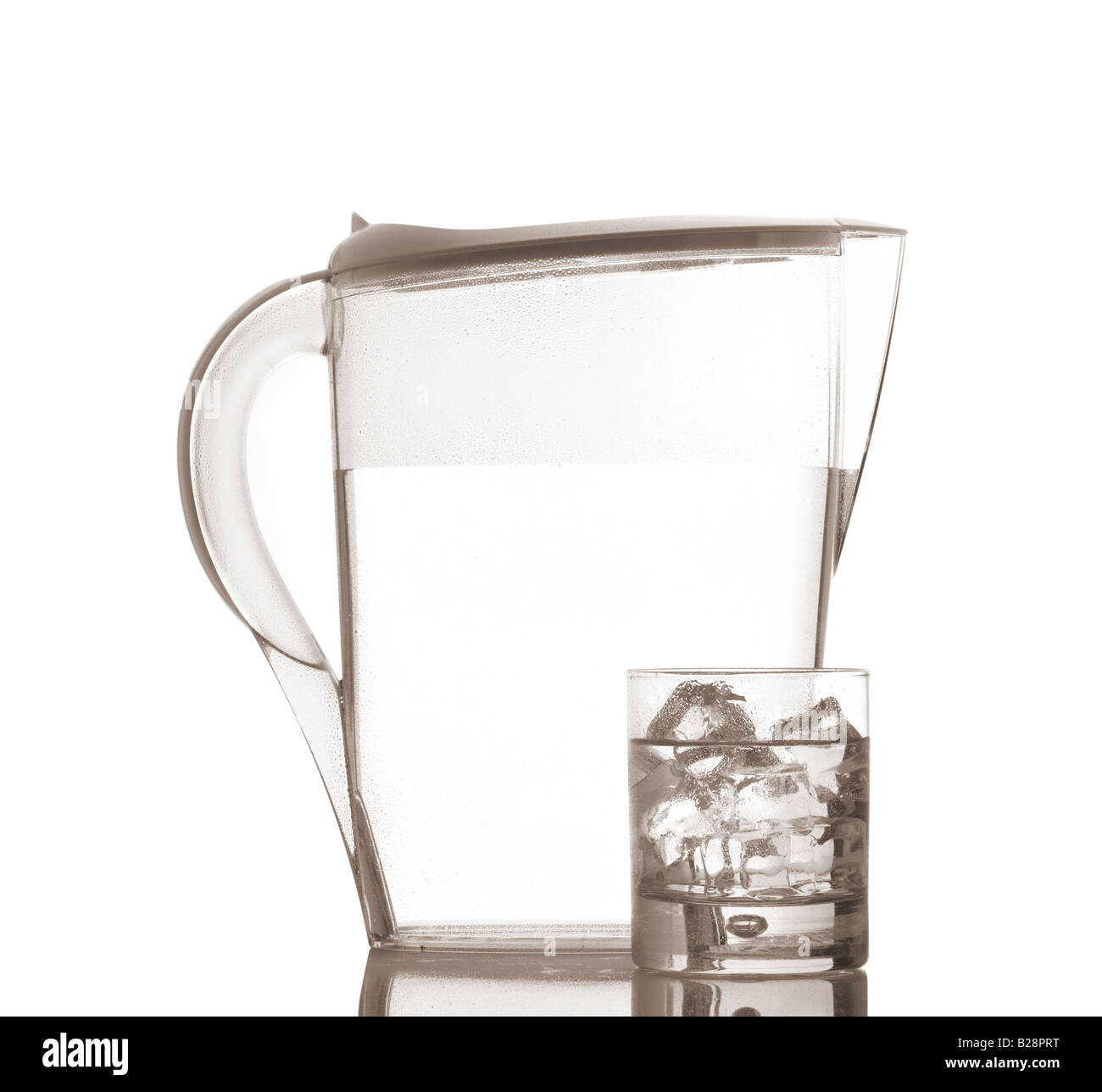 Pitcher and glass with ice cubes of mineral water reflected on white ...