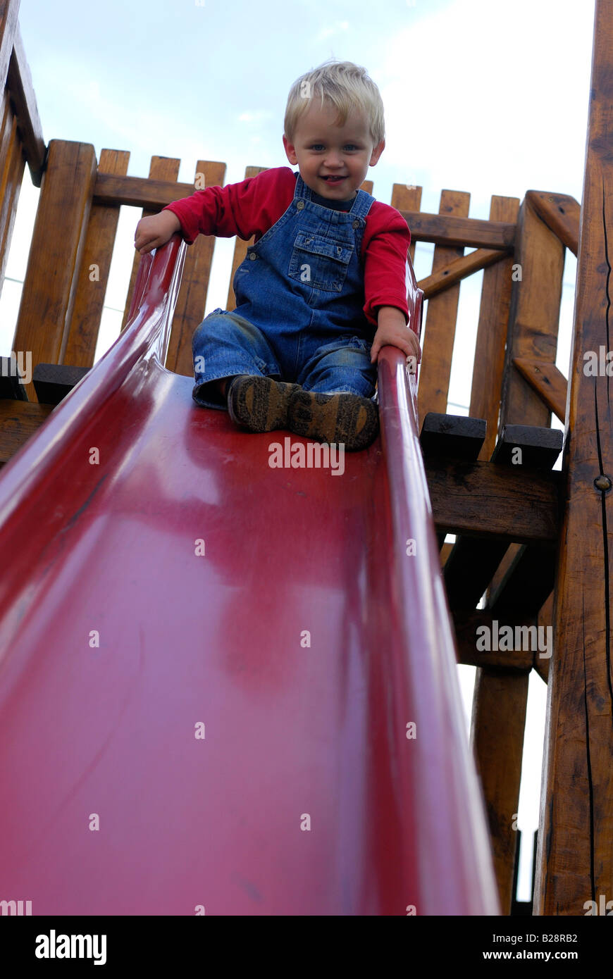 Baby blonde boy sliding down the slide on the playground Stock Photo ...