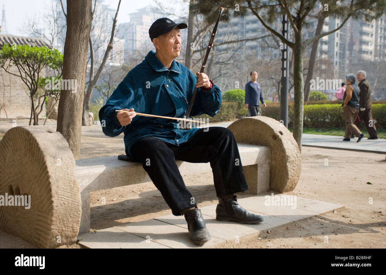 Man plays an Erhu instrument using a bow in the park by the City Wall ...