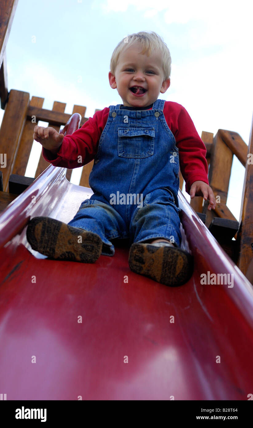 Baby blonde boy sliding down the slide on the playground Stock Photo ...