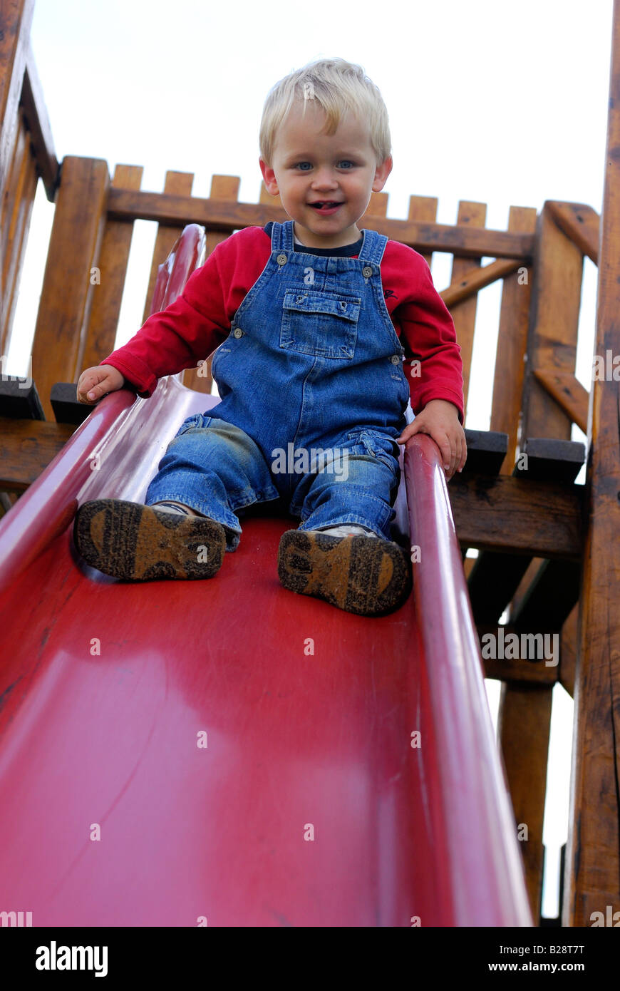 Baby blonde boy sliding down the slide on the playground Stock Photo ...