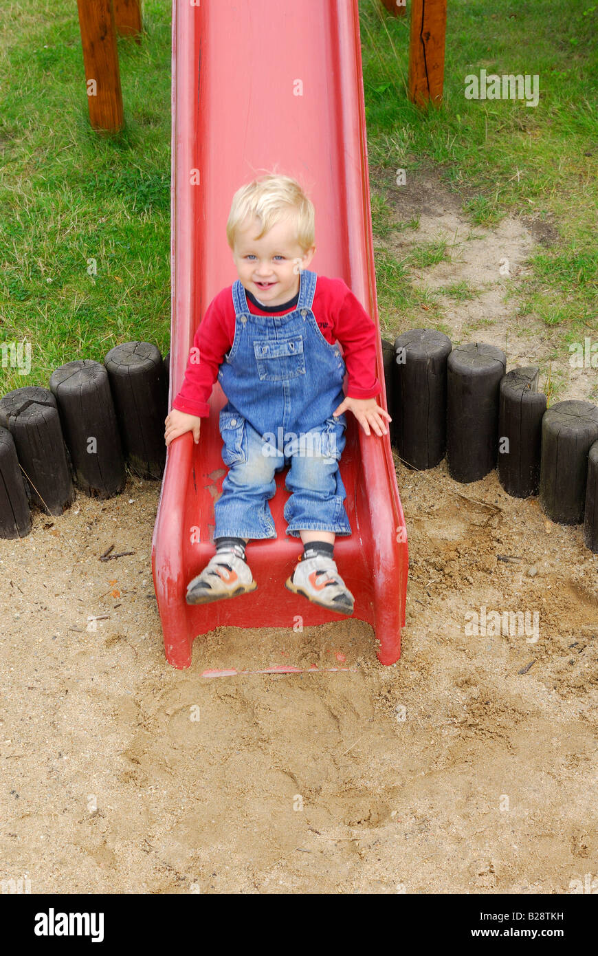 Baby blonde boy sliding down the slide on the playground Stock Photo ...