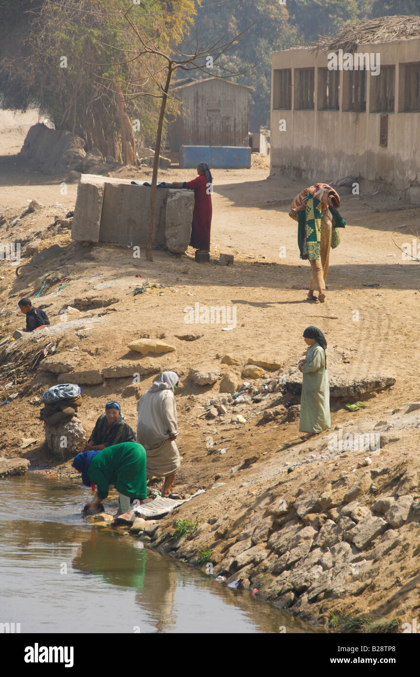 Women of the village washing their clothes and dishes in a irrigation ...