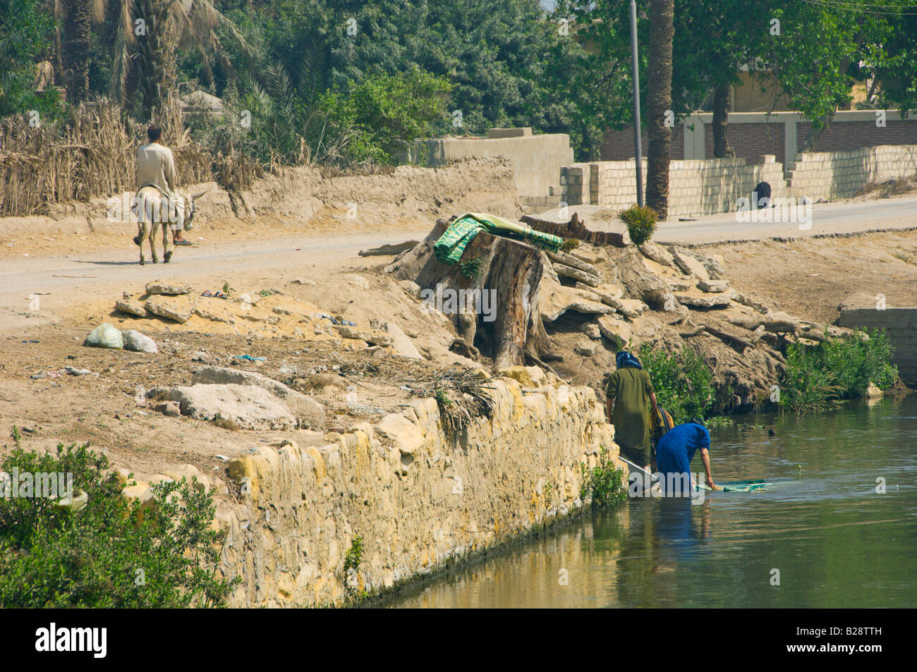 Women of the village washing their clothes and dishes in a irrigation ...