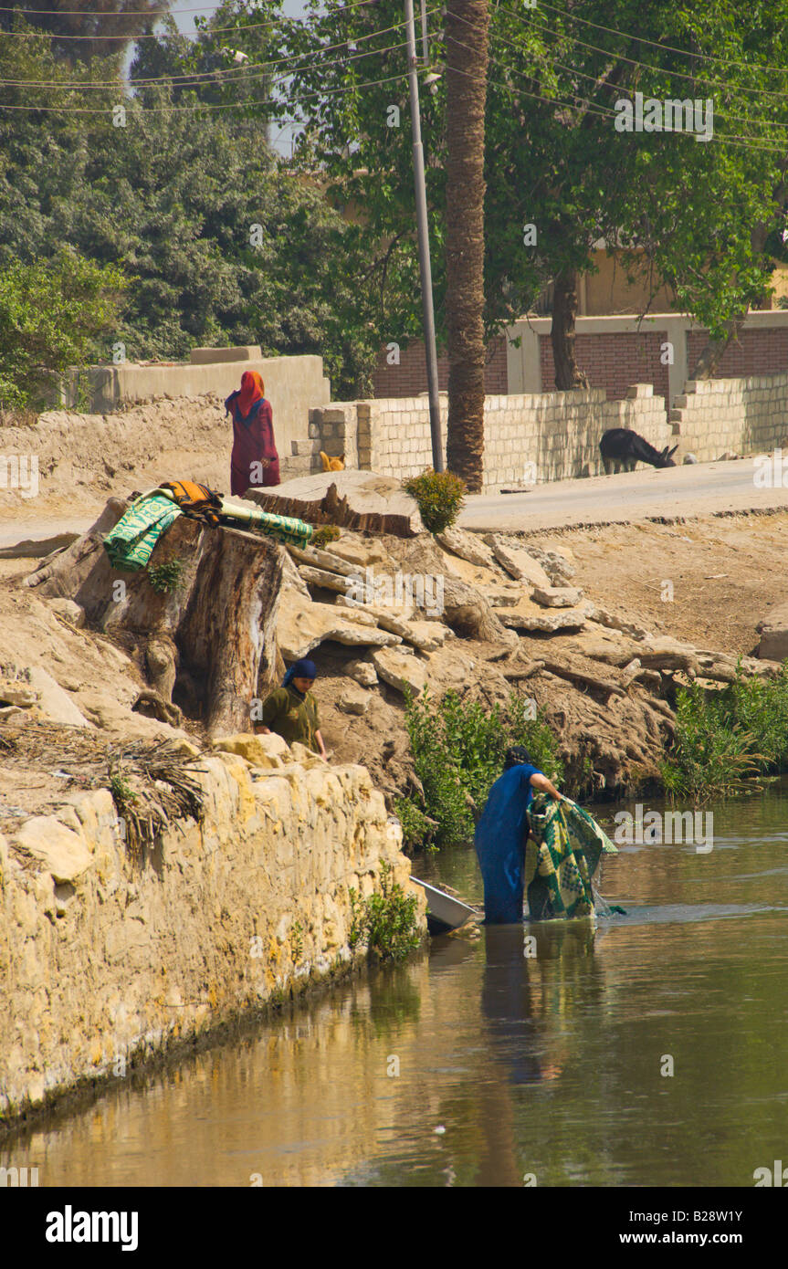 Women of the village washing their clothes and dishes in a irrigation ...