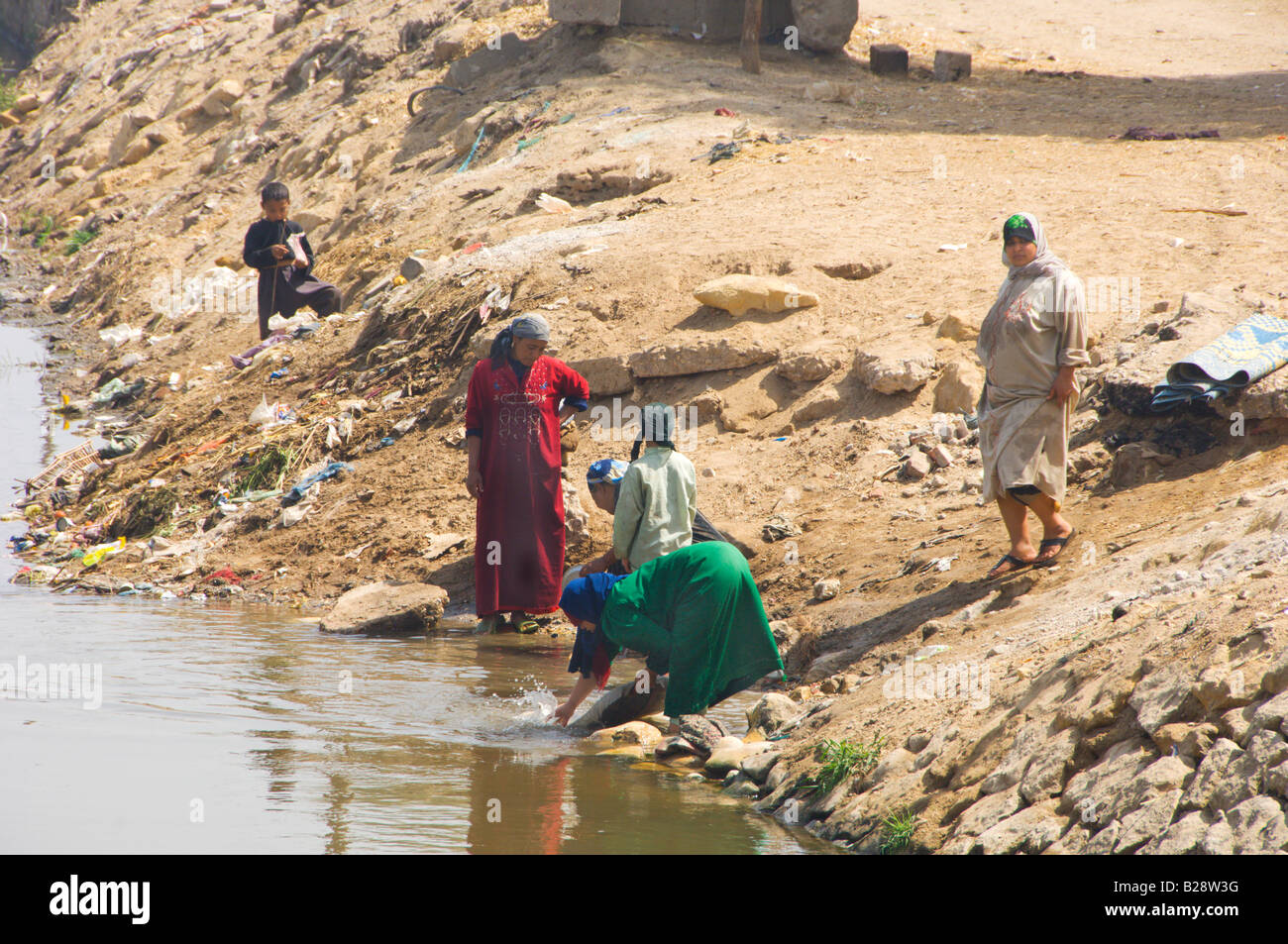 Women of the village washing their clothes and dishes in a irrigation ...