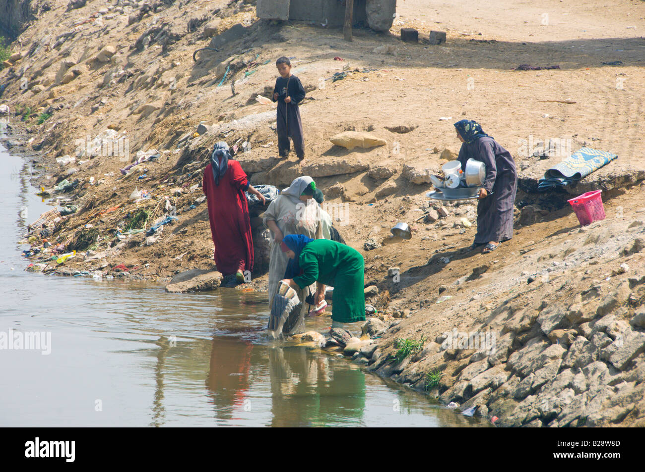 Women of the village washing their clothes and dishes in a irrigation ...