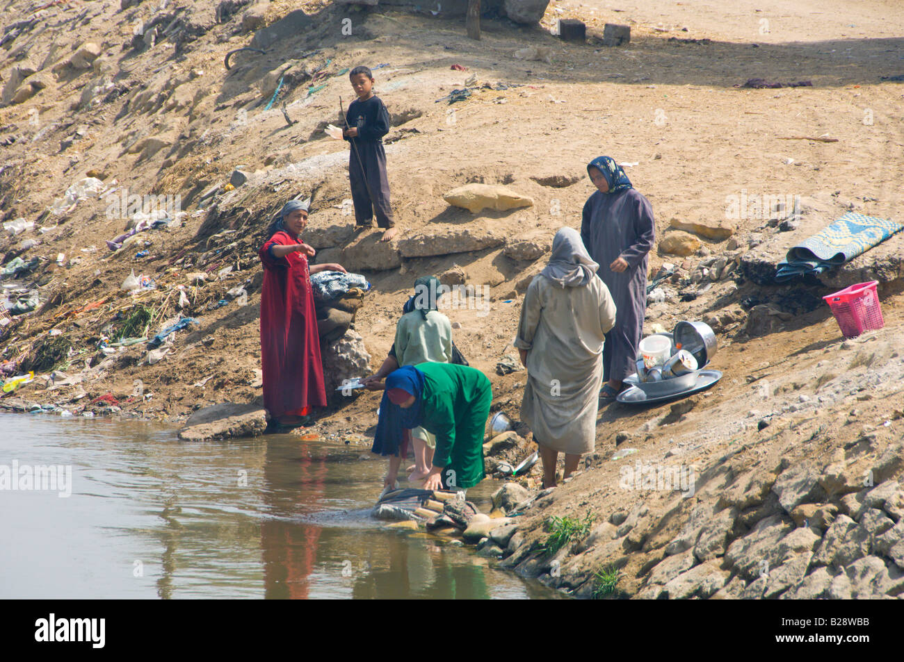 Women of the village washing their clothes and dishes in a irrigation ...
