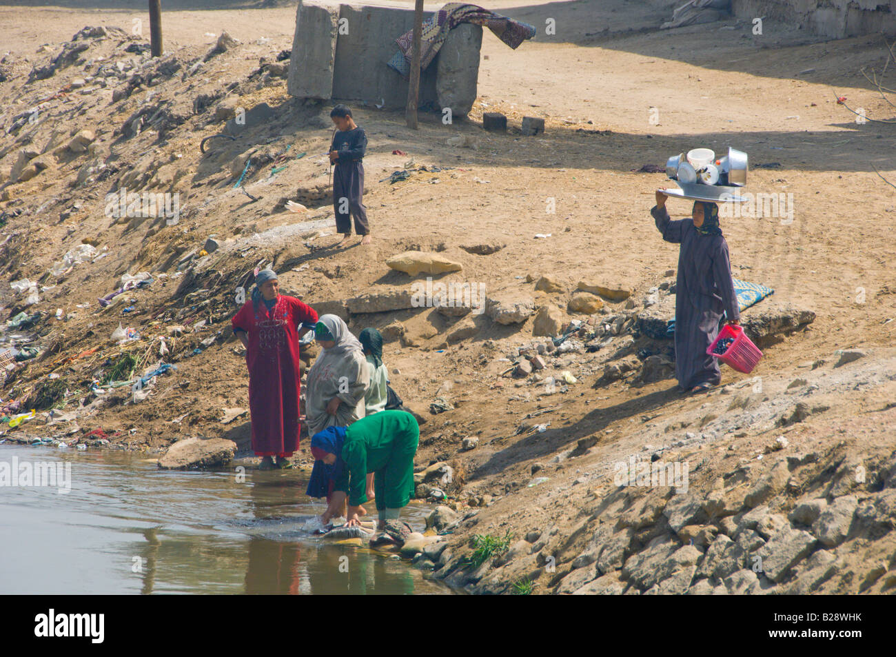 Women of the village washing their clothes and dishes in a irrigation ...