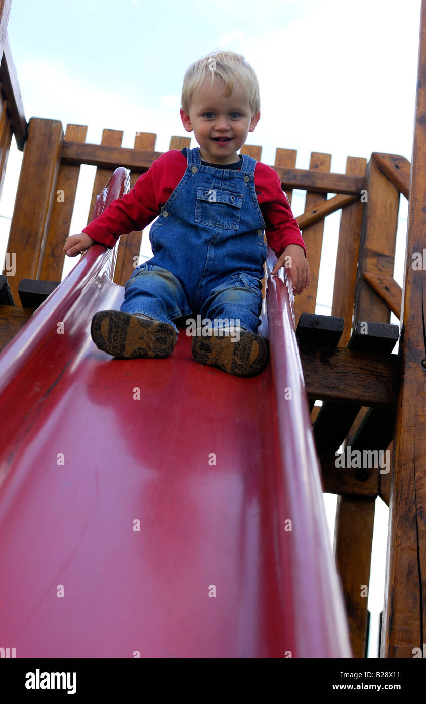 Baby blonde boy sliding down the slide on the playground Stock Photo ...
