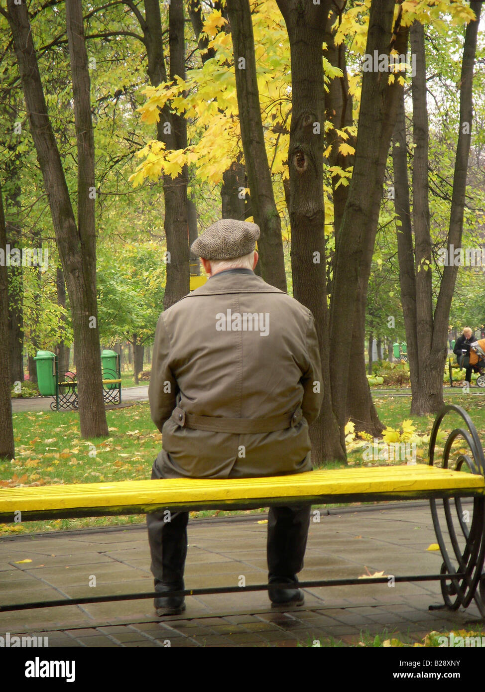 A lonely old man sitting on a bench in a park in Moscow among colorful ...