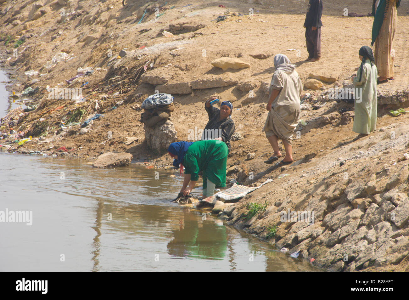 Women of the village washing their clothes and dishes in a irrigation ...
