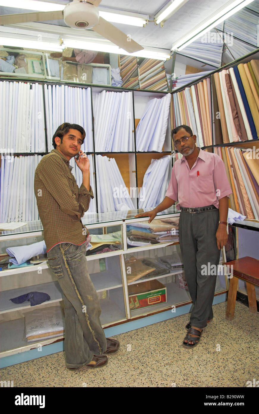 Two Indian tailors in shop with fabric for making traditional Omani ...
