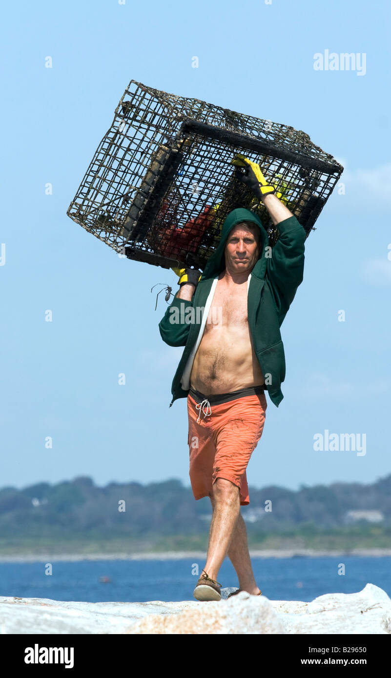 A lobster man carries a trap along the seawall in Little Compton Stock ...