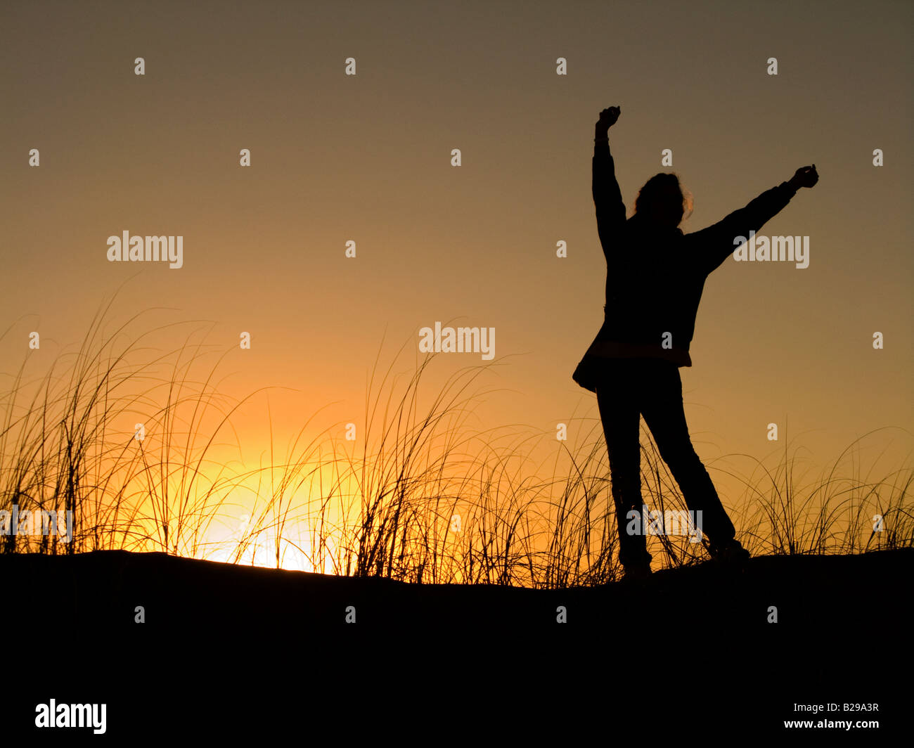 Silhouette of a young dancing teenager girl with a sunset sky in the ...