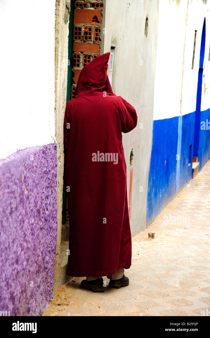 Man wearing traditional, dark red Moroccan dejellaba with the hood up ...