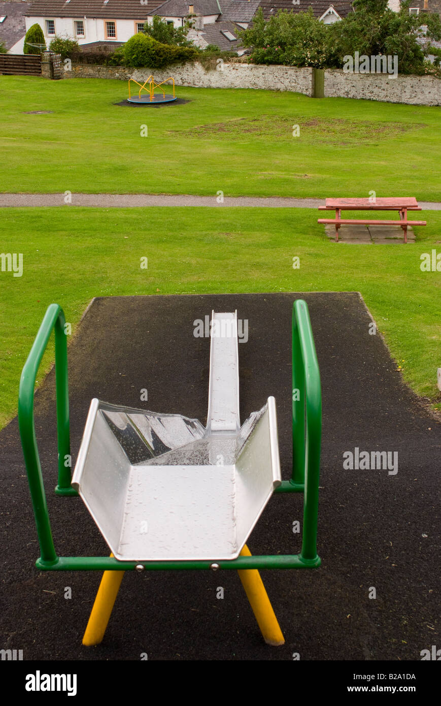 View Down a Childrens Slide with Empty Roundabout and Bench Seat in ...