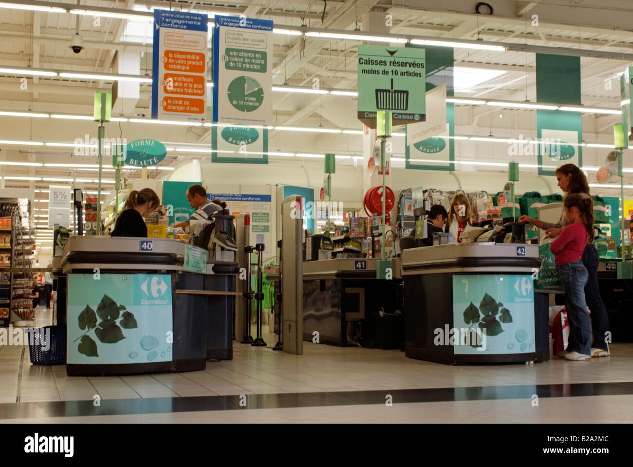 Supermarket checkout customers and cashier at a till Carrefour store ...
