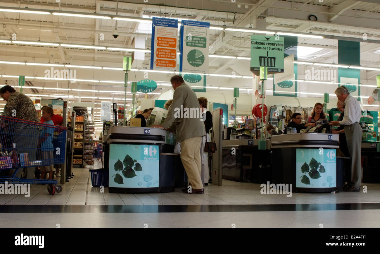 Supermarket checkout customers and cashier at a till Carrefour store ...