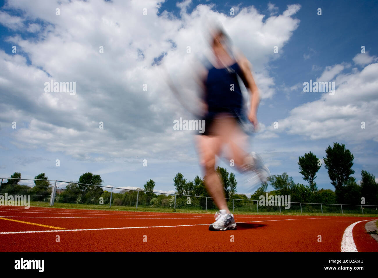 Runner captured at speed on track from a low angle, dramatic sky Stock ...