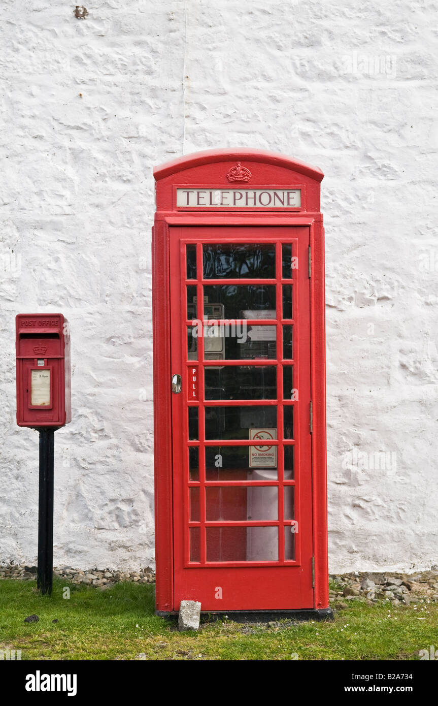 Red British telephone booth and rural post box next to white wall ...
