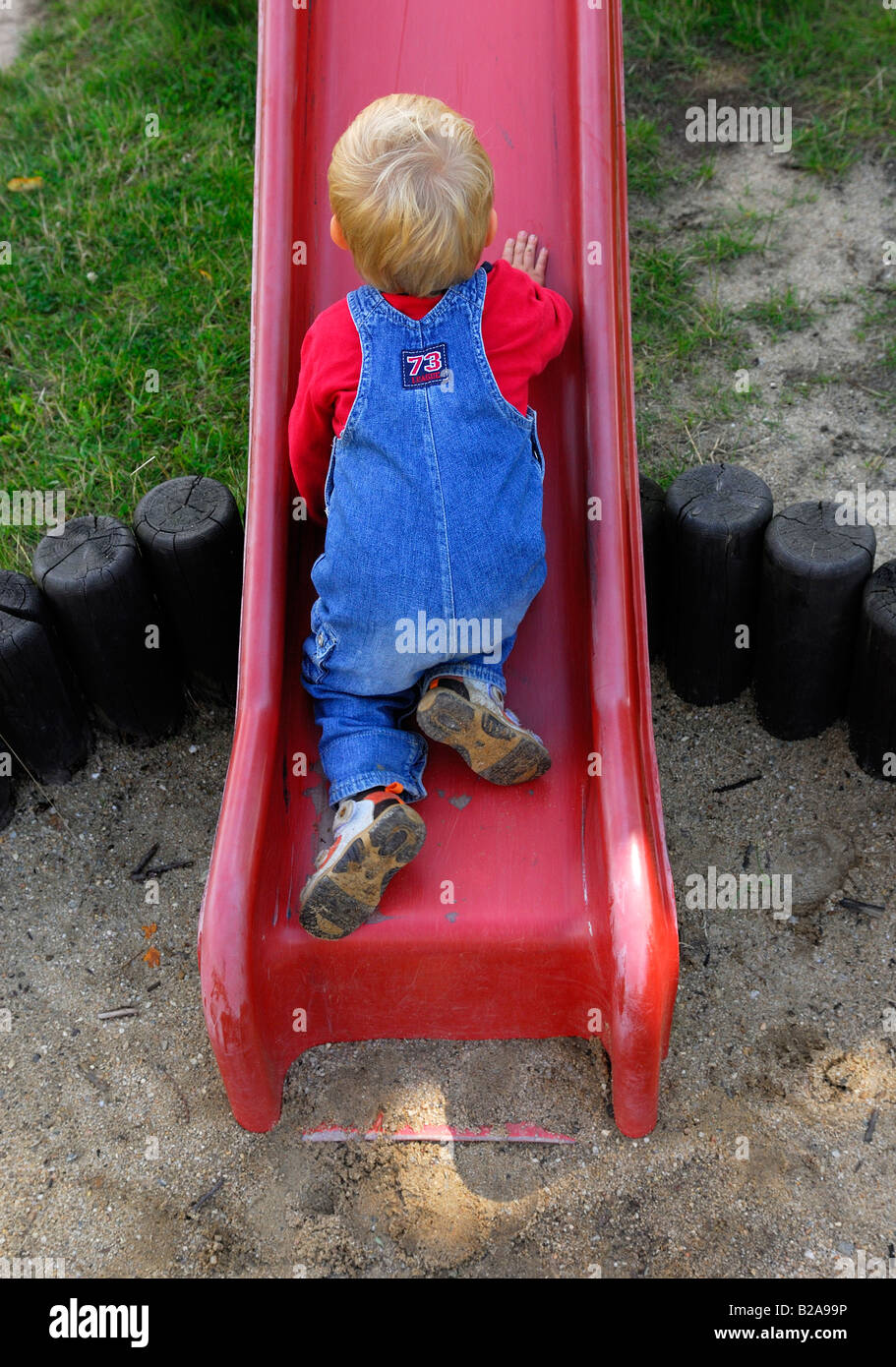 Baby blonde boy sliding down the slide on the playground Stock Photo ...
