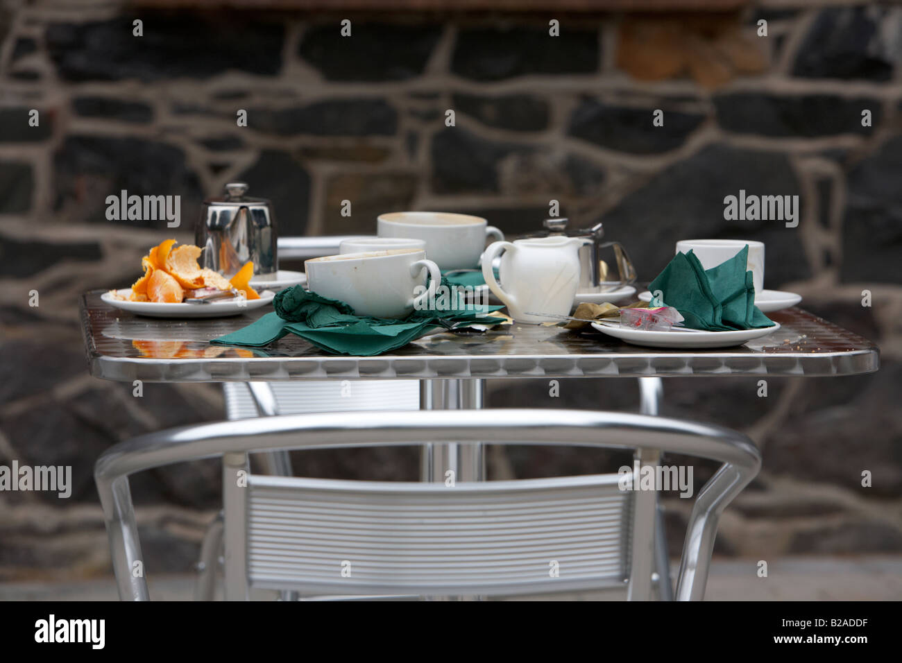 metal cafe table with remains of lunch left on it untidy and uncleaned ...