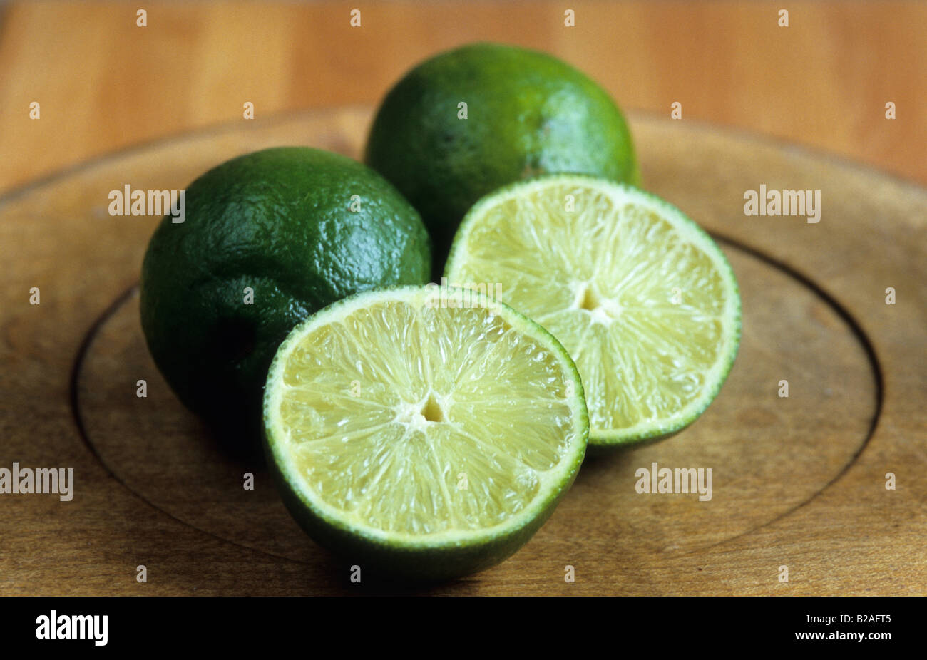 limes cut in half on wooden kitchen board Stock Photo - Alamy