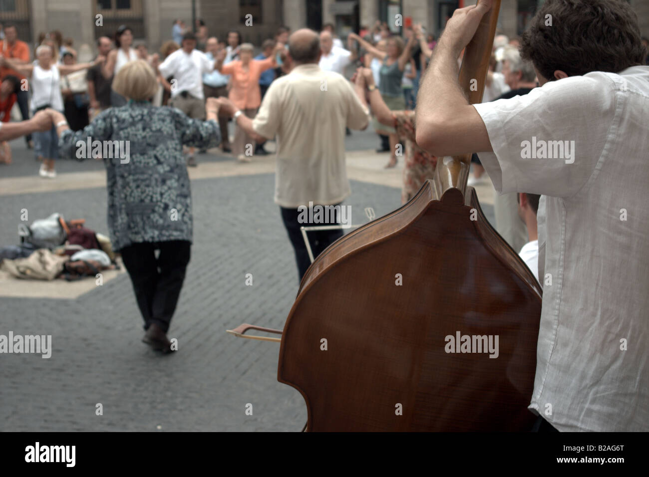 Man playing the double-bass as people form a ring to dance the 'sardana ...
