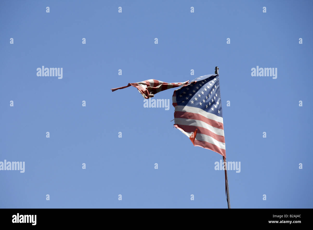 one damaged american flag flying in blue sky Stock Photo - Alamy