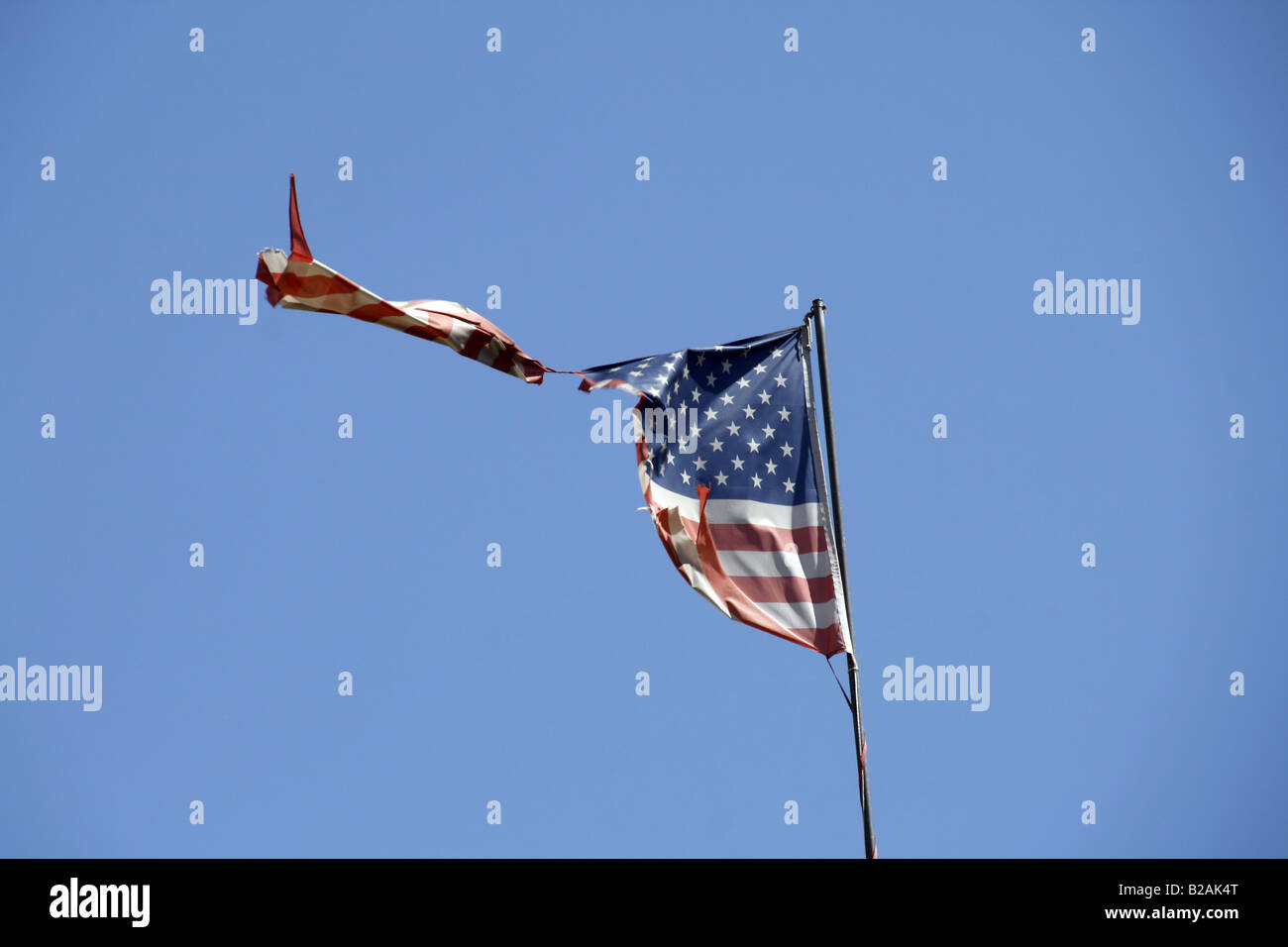 one damaged american flag flying in blue sky Stock Photo - Alamy