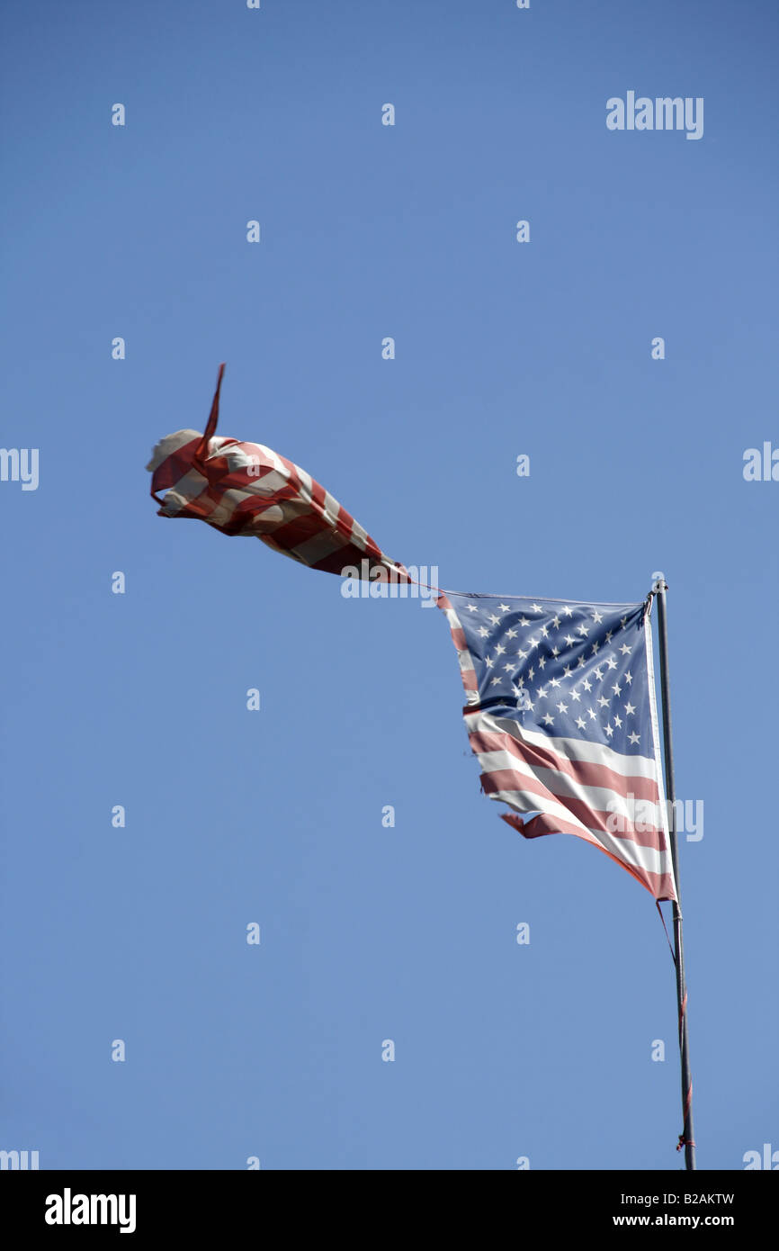 one damaged american flag flying in blue sky Stock Photo - Alamy