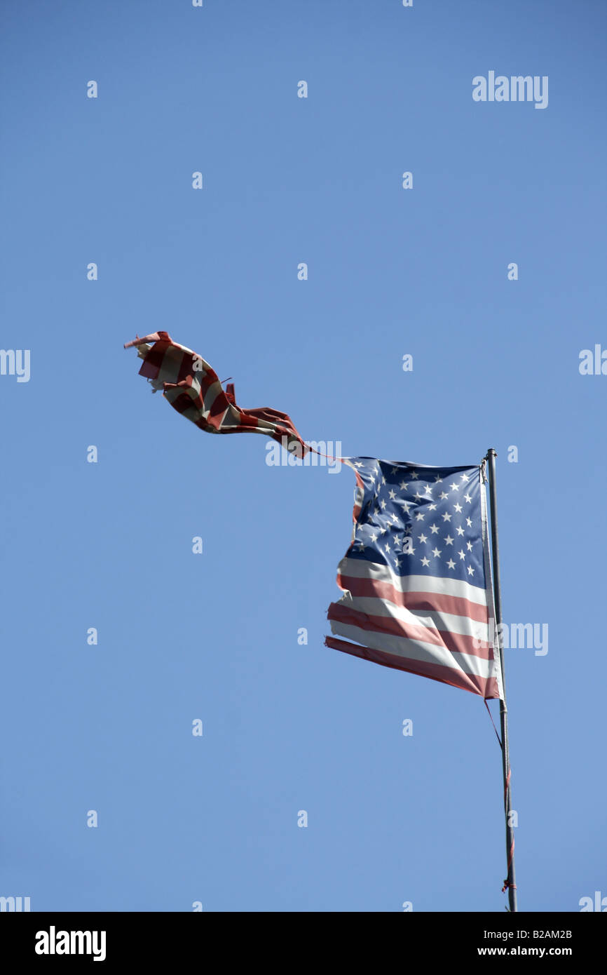 one damaged american flag flying in blue sky Stock Photo - Alamy