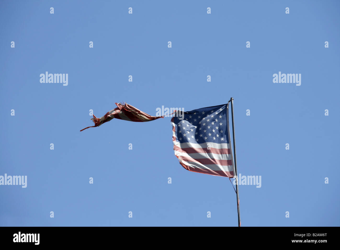 one damaged american flag flying in blue sky Stock Photo - Alamy